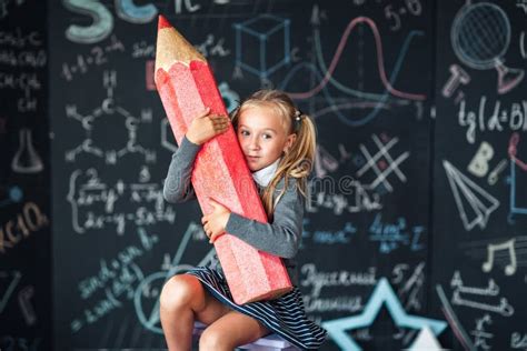 回到学校！女孩在她的手上坐与非常大红色铅笔在学校反对有学校惯例的黑板 库存照片 图片 包括有 摄影 会议室 150690332