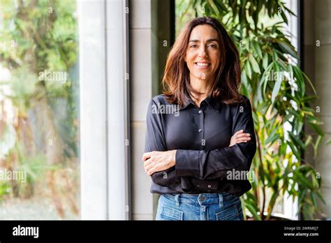 Confident Woman Entrepreneur With Arms Crossed Stands In An Office Environment Smiling And