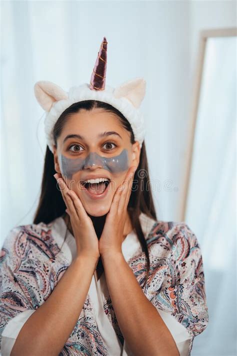 woman applying facial mask on her face looks at the camera stock image