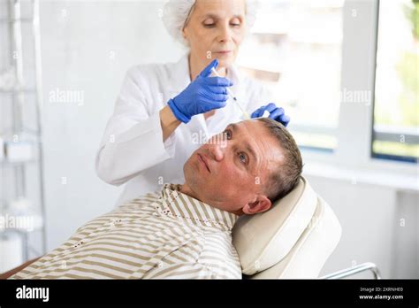 Mature Woman Doctor Gives Injection And Performs Procedure Of Lip Augmentation Of Male Patient