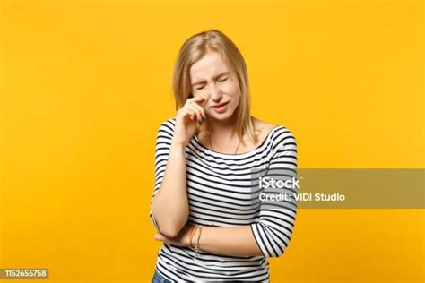눈을 감고 울고 스튜디오에서 노란 주황색 벽 배경에 고립 된 눈물을 닦아 줄무늬 옷에 불쾌 한 젊은 여자 사람들은 진심으로 감정 라이프 스타일 개념입니다 복사 공간을 모의