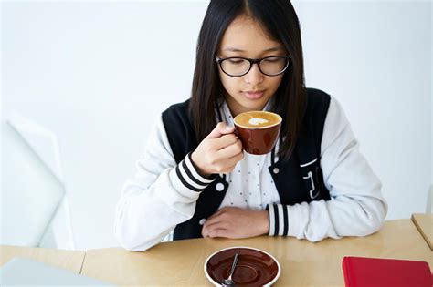 안경 흰색 프로 모션 배경 복사 공간에 잠겨있는 십 대 Hipster 여자 얼굴 카푸치노와 아트 폼 잡고 앉아 휴식 시간 동안 뜨거운 아로마 커피를 즐기는 젊은 아시아 모델