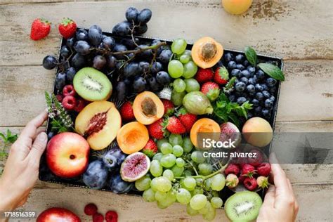 나무 테이블에 과일 쟁반을 들고 있는 여성의 손 클로즈업 과일에 대한 스톡 사진 및 기타 이미지 과일 딸기 포도 Istock