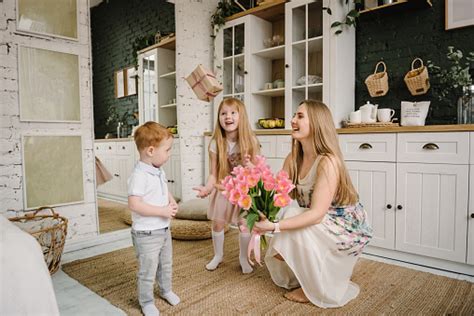 생일 축하해요 아이들과 함께 엄마는 놀랐다 아이들은 어머니를 축하하고 집에 있는 부엌에서 튤립 꽃다발을 선물합니다 어머니의 날