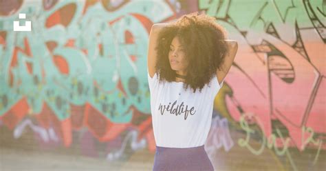 흰 셔츠와 검은 레깅스를 입은 여자가 낙서가 있는 벽 근처에 서 있다 사진 Unsplash의 무료 회색 이미지