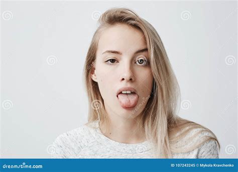 Disgusted Pretty Young Woman With Blonde Hair Sticking Out Tongue