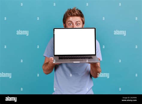 portrait of man hiding behind white empty screen laptop surprised with