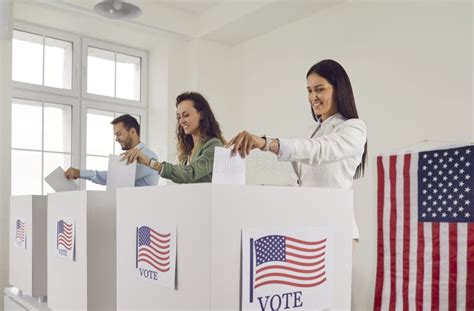 American Citizens Standing In A Row At Polling Station And Putting Their Ballots In Voting Booth