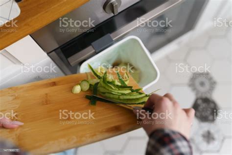 쿡은 분해를 위해 Bokashi 용기에 오이 껍질을 던집니다 퇴비 통에서 유기 음식물 쓰레기를 재활용하는 여성 가정 주방에 대한