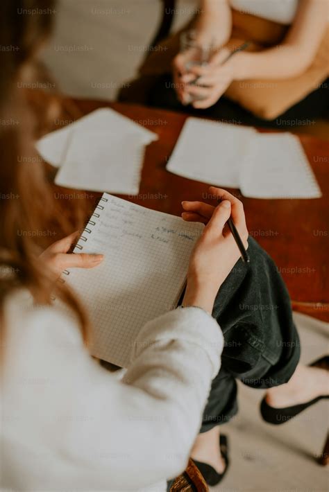 탁자에 앉아 종이에 글을 쓰는 여자 사진 Unsplash의 옹호 이미지