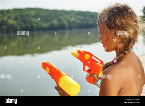 Girl Playing With A Squirt Gun At A Lake On The Summer Holidays Stock