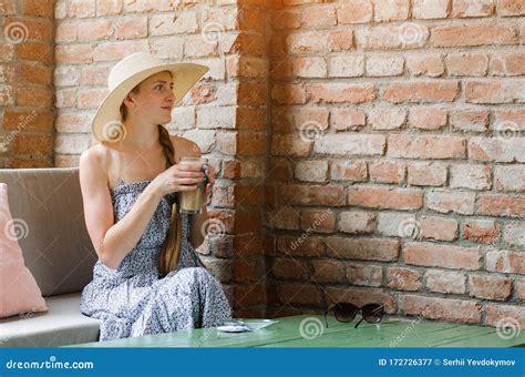 Young Woman In Straw Hat And Long Dress Drinking Beverage Against Brick Wall Stock Image Image