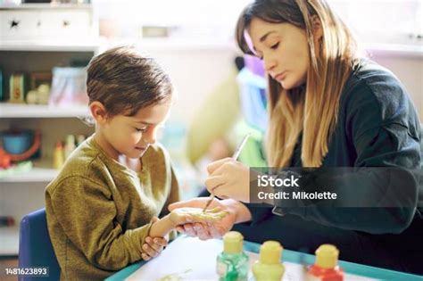 아동 발달 또는 학습을 위해 놀이방에서 어머니와 아들과 함께 교육 그림 또는 예술 가족 그림 그리기 또는 숙제와 여성 교사 및 학생 소년이 창의력을 발휘하면서 유대감을
