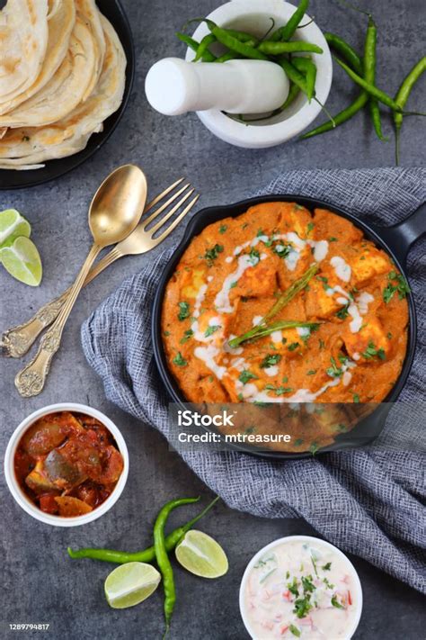 회색 치즈 천 두꺼운 그레이비 크림 토마토 인도 향신료와 함께 제공되는 수제 샤히 파네어 의 요리 팬 이미지 포크와 숟가락 라이타 그릇 처트니 박격포와 유봉 높은 전망 퍼닐