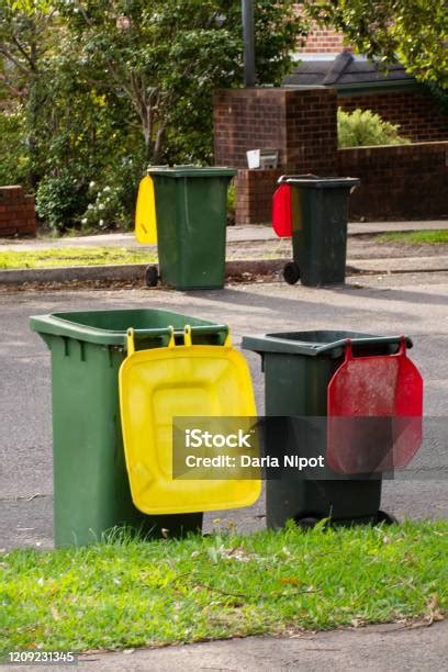 일반 및 재활용 가정용 쓰레기를 위한 다채로운 뚜껑이 있는 호주 쓰레기 바퀴달린 쓰레기통이 거리 연석에 줄지어 서서 쓰레기