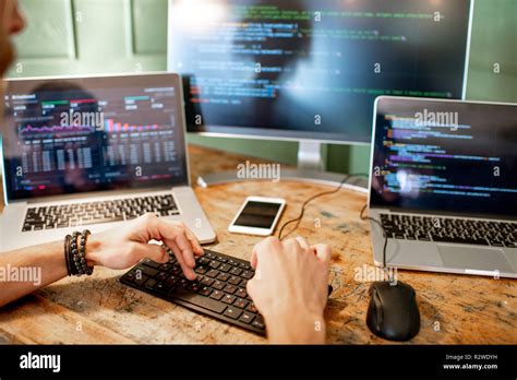 Young Programmer Writing A Program Code Sitting At The Workplace With
