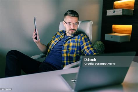 젊은 이루어지지 직원 들고 한 손으로 노트북에 다른 지주 태블릿에 늦은 밤 사무실에 앉아있는 동안 거리가 먼에 대한 스톡 사진 및 기타 이미지 Istock