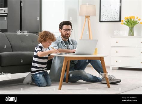 Man Working Remotely At Home Father Using Laptop While His Son Drawing At Desk Stock Photo Alamy