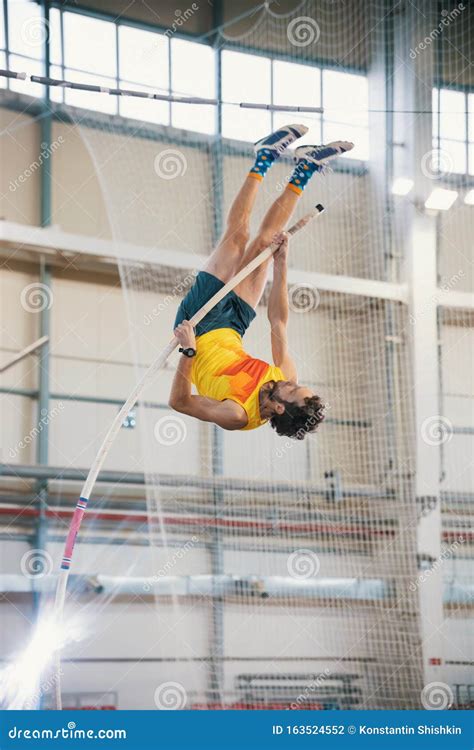 Pole Vaulting Indoors A Athletic Man Jumping Over The Bar Leaning