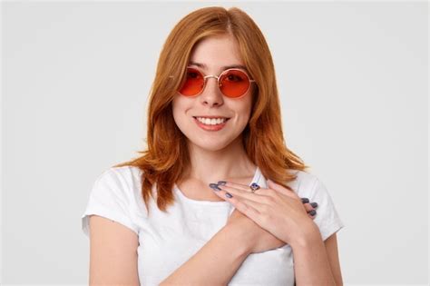 Free Photo Ginger Female With Positive Smile Keeps Hands On Chest