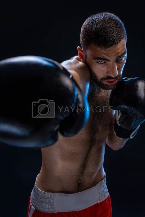 Portrait Of Tough Male Boxer Posing In Boxing Stance Against Black
