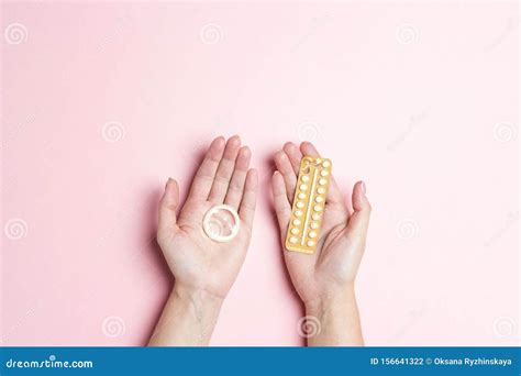 Contraceptive Means A Condom And Birth Control Pills In A Woman Hands