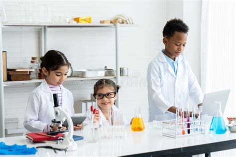 Two Little Asian Girls And One Young African Boy In White Lab Coat With