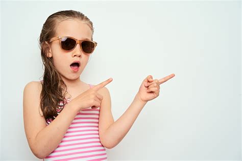 젖은 머리를 가진 작은 유치원 소녀는 흰색 배경 착용 수영복과 선글라스는 얼굴 표정 데 손가락으로 가리키는에 대 한 촬영 Contingency Plan에 대한 스톡 사진 및