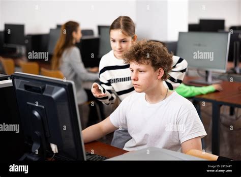 Babe Using Computer To Help Girl To Solve Problem In Classroom Stock Photo Alamy
