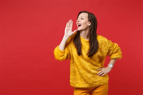 노란색 모피 스웨터에 젊은 여자의 초상화 스튜디오에서 밝은 빨간색 벽 배경에 고립 된 손 제스처와 함께 말하기 사람들은 진심으로