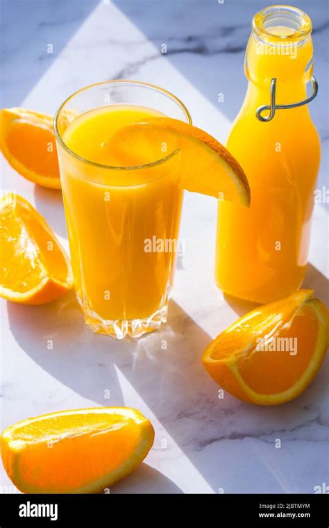 Glass bottle of fresh squeezing Orange juice with sliced fruits on concrete background. Fruit ...