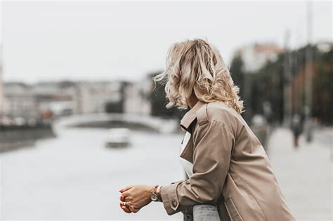 곱슬 머리를 가진 중년의 금발 여성이 도시의 강 제방에 서 있습니다 40 44세에 대한 스톡 사진 및 기타 이미지 40 44세 가을 강 Istock