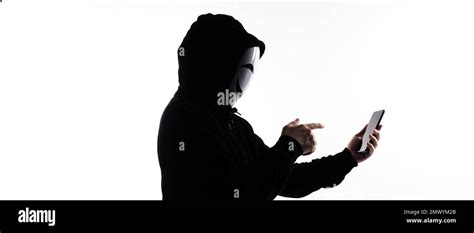 Hacker Anonymous And Face Mask With Smartphone In Hand Man In Black Hood Shirt Holding And