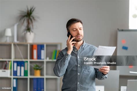 사무실에서 일하는 진지한 중년 사업가 책상 옆에 서서 문서를 들고 전화 대화를 나눈 35 39세에 대한 스톡 사진 및 기타 이미지 35 39세 건설업자 남성 Istock