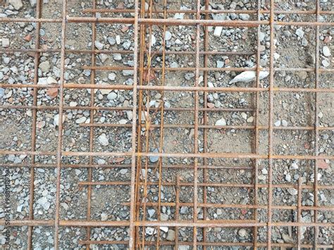 An Overhead Shot Of Rusty Steel Reinforcement Bars Arranged In A Grid Pattern Over Compacted