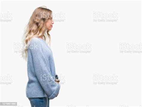 사이드로 보고 격리 된 배경 위에 아름 다운 젊은 금발의 여 자가 입고 겨울 스웨터 긴장 자신감 미소와 자연 스러운 얼굴 프로필