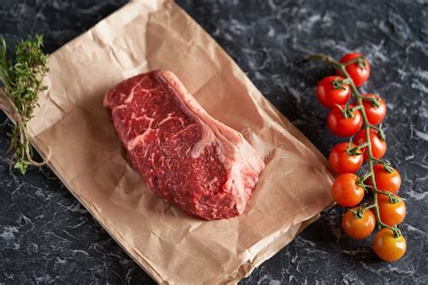 Fresh Seasoned Juicy New York Steak On Food Paper With Tomatoes On A