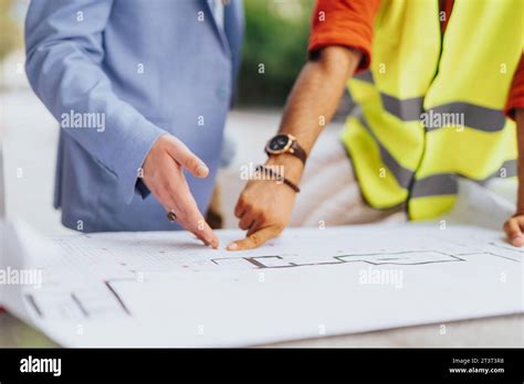 Architects Engineers And Designers Collaborate Outdoors Reviewing Architectural Blueprints