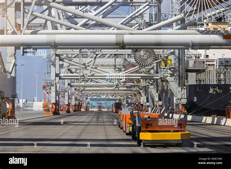 Automated Guided Vehicles Moving Shipping Containers To And From Gantry Cranes In A Port