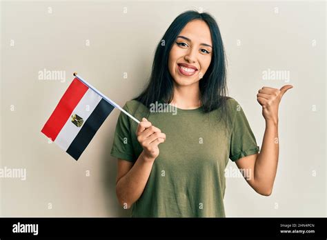 Young Hispanic Girl Holding Egypt Flag Pointing Thumb Up To The Side