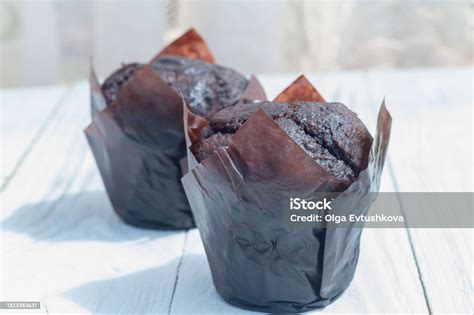 부드러운 반죽으로 만든 맛있는 초콜릿 머핀은 흰색 나무 테이블에 종이로 싸여 있습니다 갈색에 대한 스톡 사진 및 기타 이미지 갈색 달콤한 음식 러시아 Istock