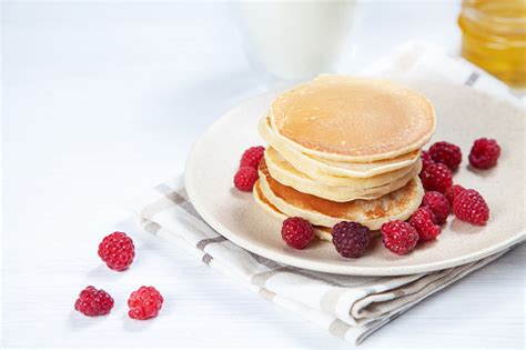 아침 식사로 꿀이나 마플 시럽과 베리를 곁들인 클로즈업 팬케이크 아침 식사 디자인을 위한 공간을 복사합니다 홈메이드 아메리칸 팬케이크 스낵 우유 한 잔과 팬케이크 0명에