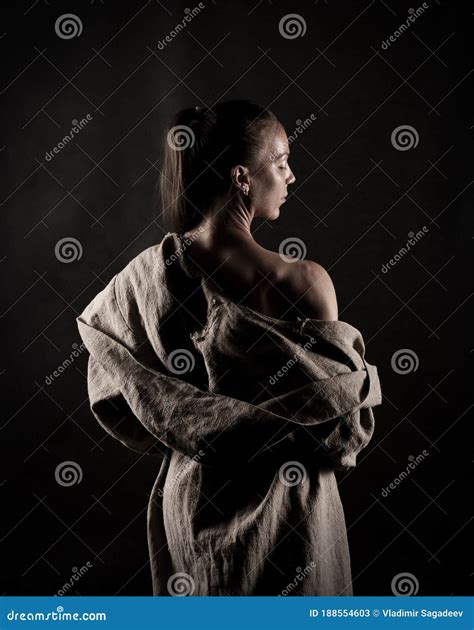 Una Joven Con Impermeable De Tela Gruesa En Su Cuerpo Desnudo Está De Fondo Negro Imagen de