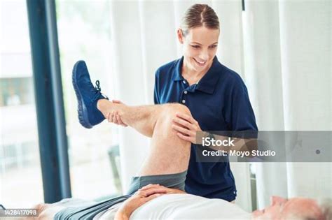 노인의 다리를 움직이는 의사 물리 치료 테이블에서 엉덩이 운동과 이동성 향상을 돕기 위해 운동합니다 물리 치료 요가 스트레칭 운동 및 유연성을 향상시키기위한 피트니스 운동