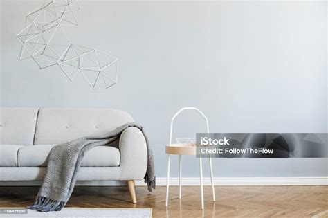 디자인 회색 소파 커피 테이블 삼각형 기하학적 조각과 열린 공간의 미니멀하고 추상적 인 인테리어 회색 배경 벽 갈색 나무 마루 객실의 현대적인 개념입니다 템플릿 실내에 대한