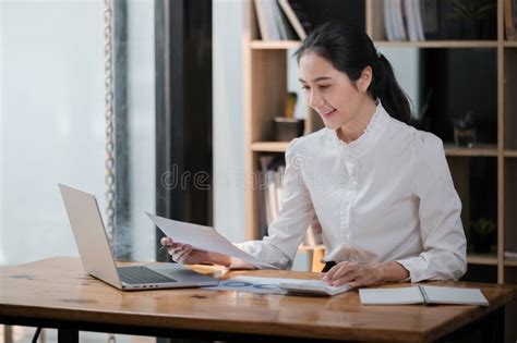Portrait Of Young Successful Asian Businesswoman Sitting At Desk