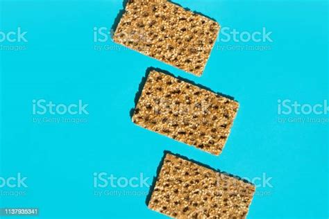 스칸디나비아 호 밀 전체 곡물 크리스피 빵에서 참 깨를 사용한 대각선 구성의 파란색 배경에 단색 거친 그림자 하드 라이트 유행 미니 멀 팝 아트 스타일입니다 균형 잡힌 식이