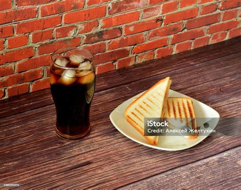 하얀 세라믹 접시에 고기와 야채를 곁들인 신선한 샌드위치 두 개와 나무 테이블 위에 얼음을 넣은 콜라 한 잔 0명에 대한 스톡 사진 및 기타 이미지 Istock