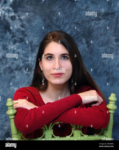 Female Teen Sits Poised In A Lime Green Wooden Chair Turned Backwards Her Arms Are Resting