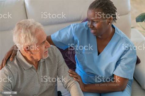 흑인 여성 재택 간호 간호사가 집 거실에서 노인 환자를 말하고 위로하는 모습 2명에 대한 스톡 사진 및 기타 이미지 2명 가정간병인 간호사 Istock